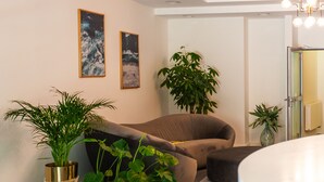 Uma sala de estar moderna com um sofá, plantas em vasos e obras de arte na parede.
