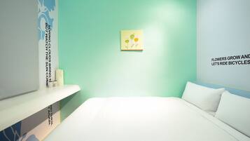 Quarto com cama, mesa de cabeceira e parede decorada com pintura floral e texto motivacional.
