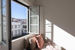 Um quarto com uma grande janela, um sofá e vista para a paisagem urbana.