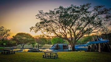 Um parque com mesas para piquenique, parquinho e uma cascata.