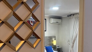 Quarto de hotel com cama, mesa de cabeceira, aparelho de ar condicionado e espelho fixado na parede.