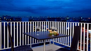 Varanda com mesa posta para dois, incluindo taças de vinho e uma cesta.
