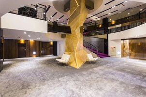 Um hall amplo com escadaria central, vários espaços de estar e design moderno.
