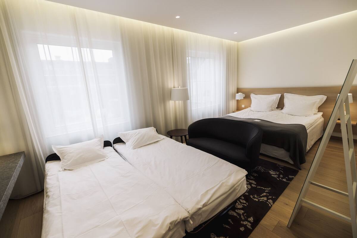 Quarto de hotel com duas camas, uma escrivaninha e um espelho.