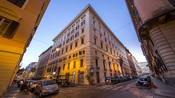 Um edifício histórico com entrada na esquina, várias janelas e rua de paralelepípedos.