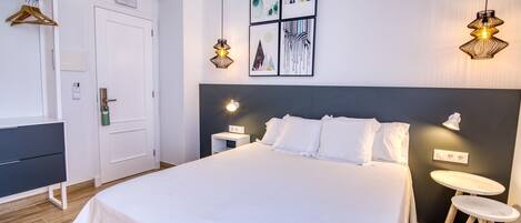 Quarto de hotel moderno com uma cama grande, mesas de cabeceira, um guarda-roupa e obras de arte nas paredes.
