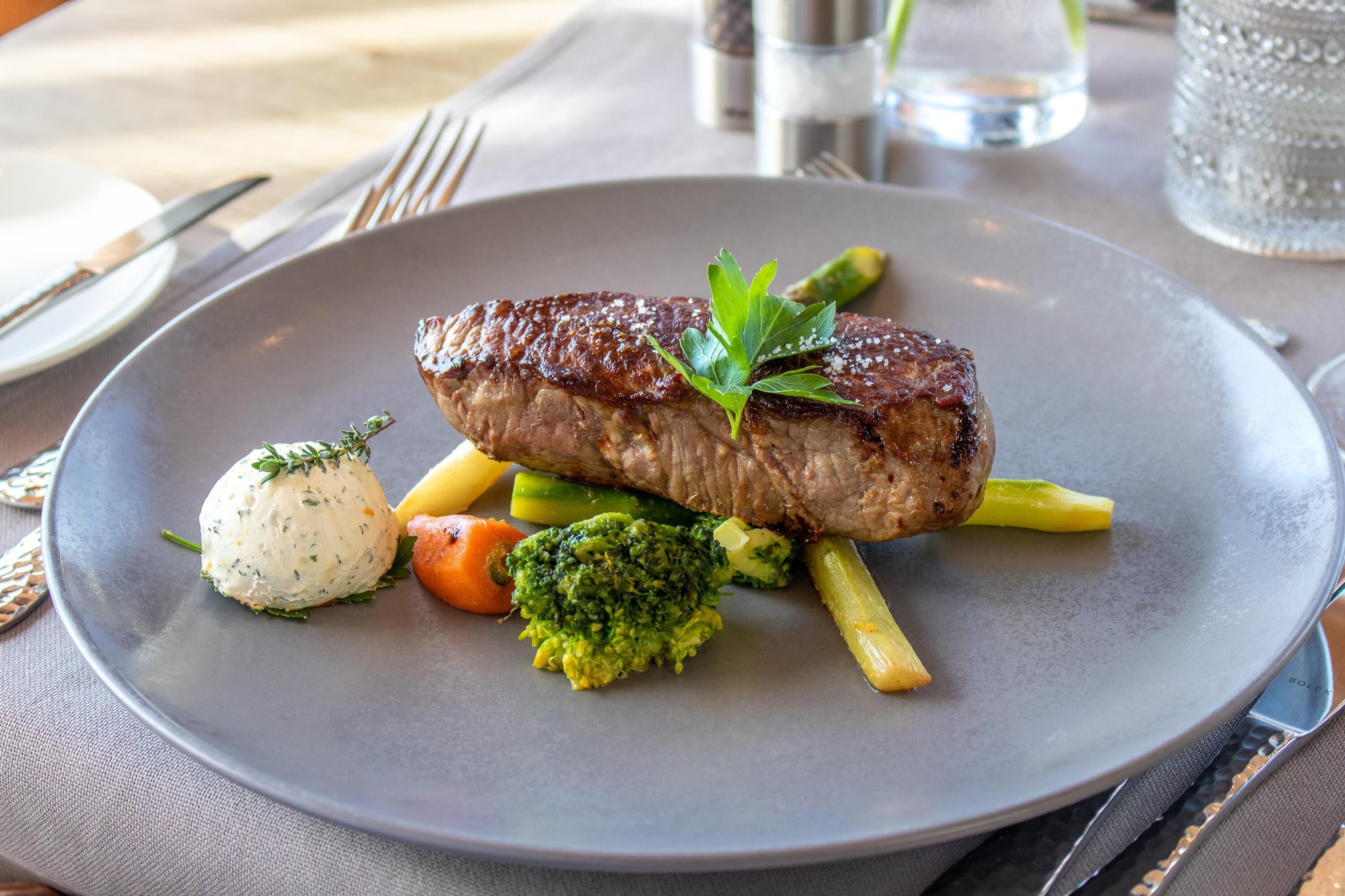 Um prato com um bife grelhado, brócolis e um pouco de manteiga de ervas.