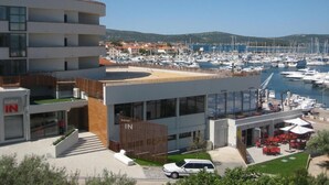 Hotel com design moderno, apresentando um terraço no telhado com área de estar externa e vista para uma marina com vários barcos.