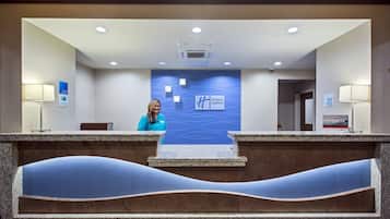 Bancada de recepção de hotel com design de ondas azuis, um recepcionista e uma placa da Holiday Inn Express.