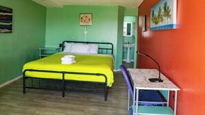 Quarto com cama, escrivaninha, cadeira, pia e um quadro na parede.