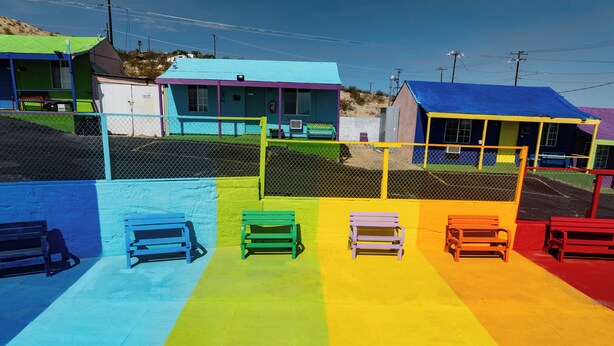 Uma área de estar ao ar livre colorida, com bancos dispostos em um padrão de arco-íris.