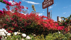 Placa do 'El Royale Hotel', com céu visível e vegetação ao redor.
