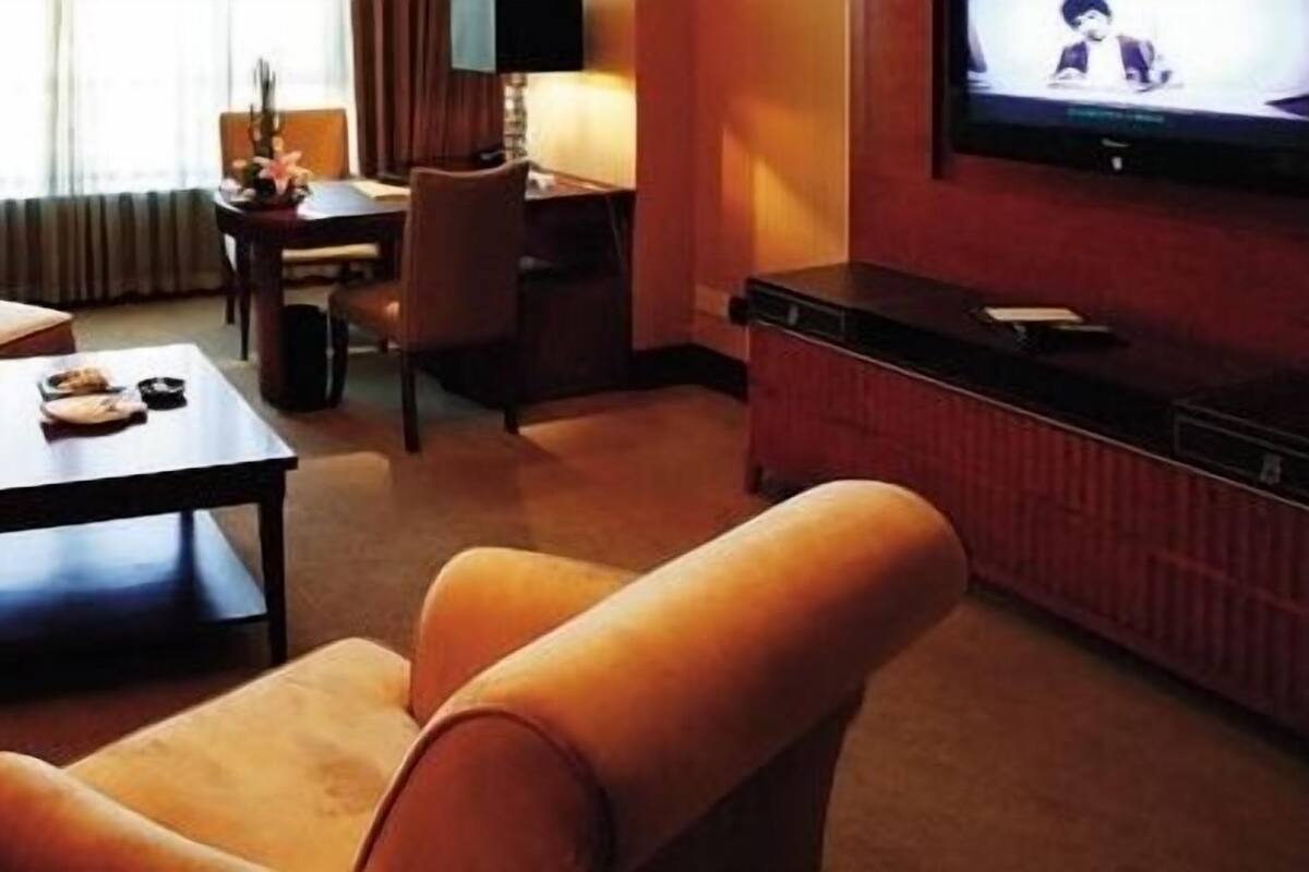 Uma sala de estar com sofá, poltronas, mesa de centro, televisão e um espaço de refeições com mesa e cadeiras.