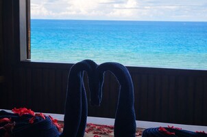 Quarto com vista para o oceano, uma janela e uma cadeira com toalha em formato de coração.