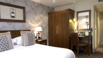 Quarto de hotel com cama, escrivaninha, cadeira, abajur, espelho e guarda-roupa.