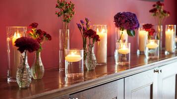 Um balcão de madeira com vários vasos de vidro contendo flores e velas.