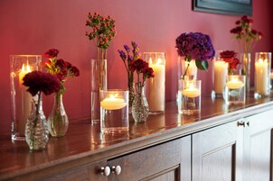 Um balcão de madeira com vários vasos de vidro contendo flores e velas.