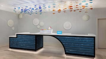 Uma receção com design azul e preto, uma placa a indicar que é um estabelecimento Hilton e elementos decorativos suspensos.