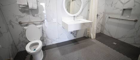 Uma casa de banho moderna com sanita, lavatório e chuveiro.