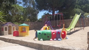 Uma área de recreação infantil com um trem, um escorrega e casinhas.