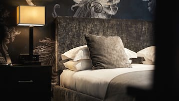 Quarto com uma cama grande, mesa de cabeceira com abajur e painel decorativo na parede.