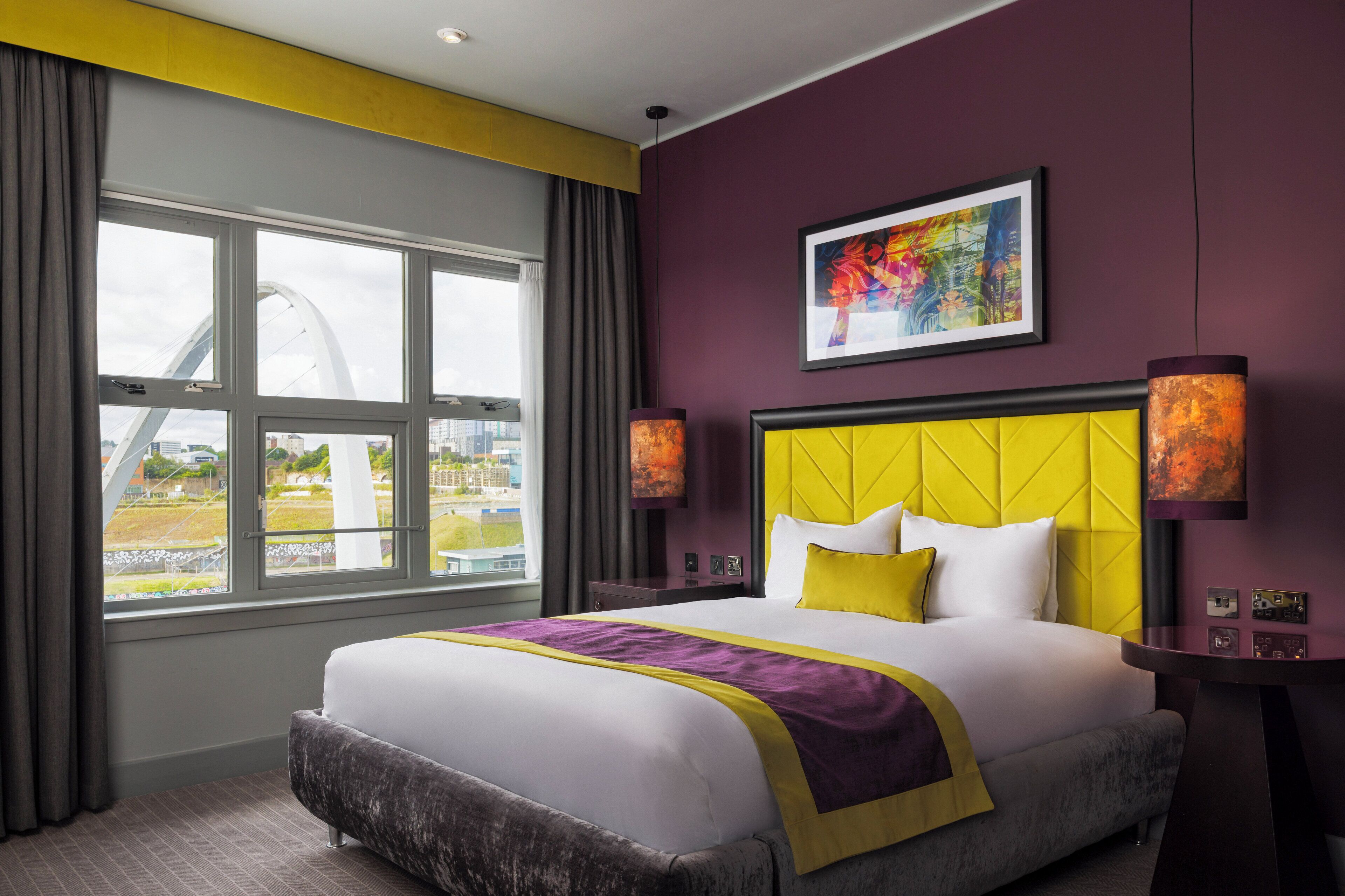 Quarto de hotel com uma cama grande, vista para uma ponte e paisagem urbana.