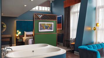 Quarto de hotel moderno com uma banheira grande, um espaço de estar aconchegante e uma janela ampla com cortinas.