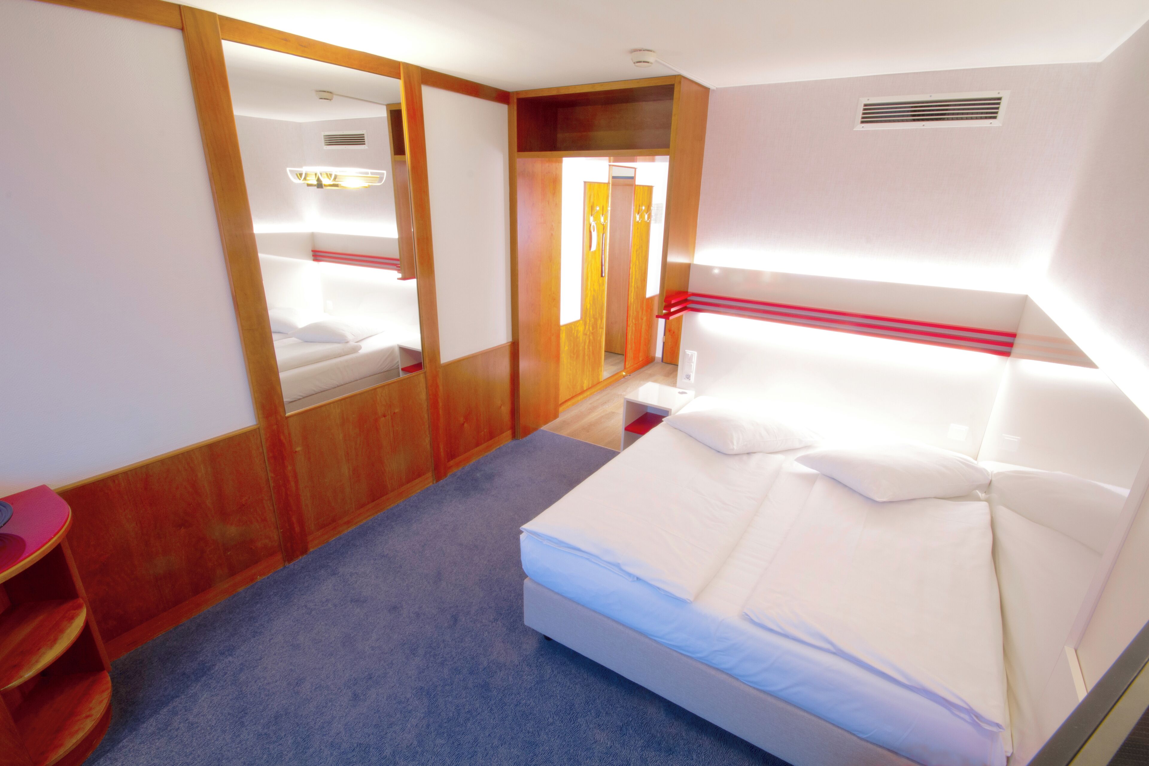 Quarto com cama, guarda-roupa de madeira e espelho.