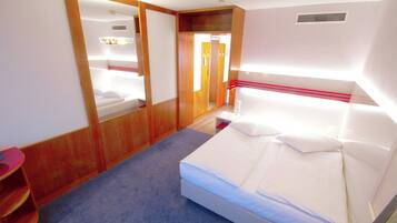 Quarto com cama, guarda-roupa de madeira e espelho.