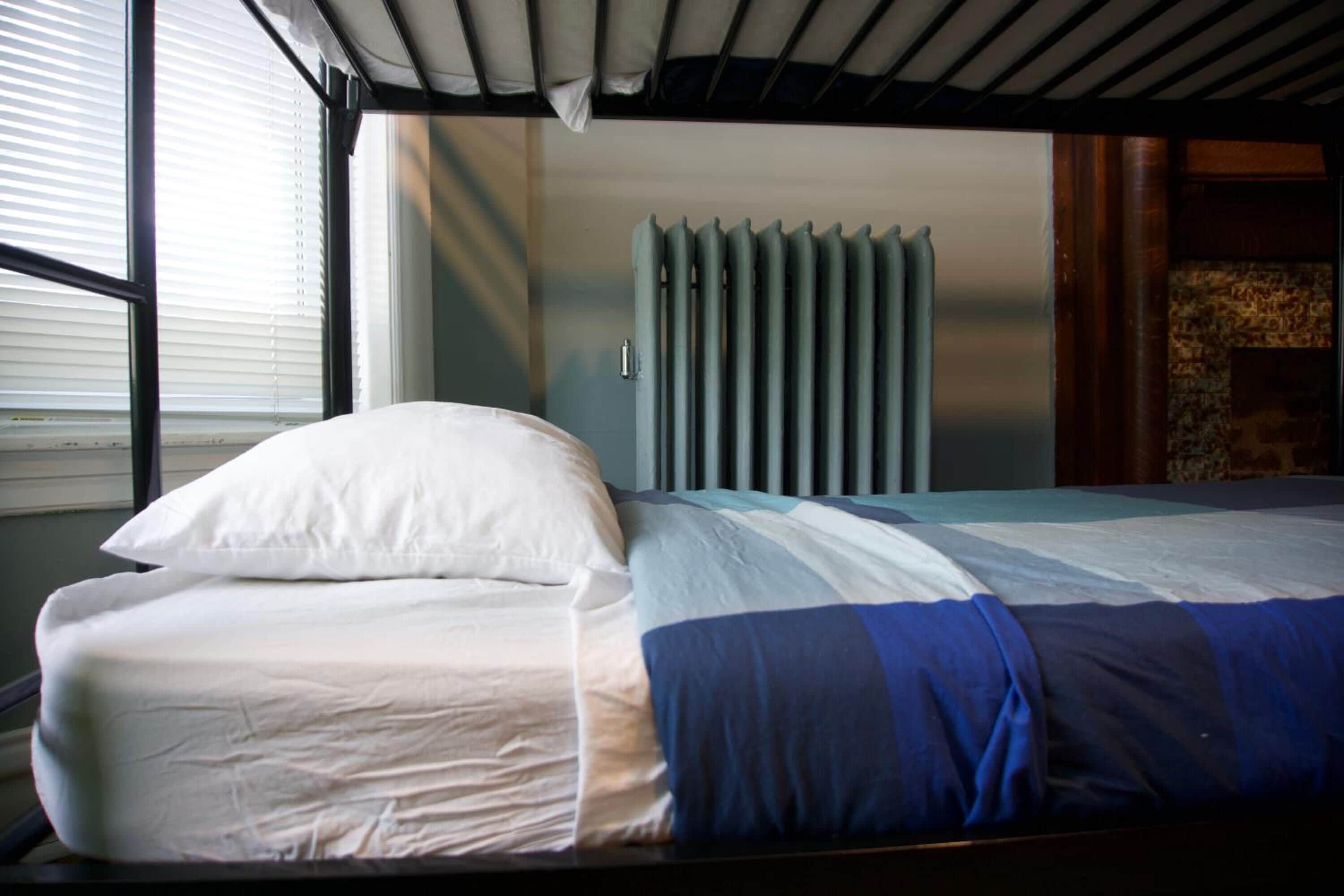 Uma cama beliche com travesseiro branco e cobertor azul e branco listrado.