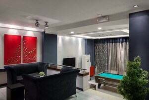 Uma sala de estar moderna com mesa de bilhar, sofá, TV e um painel decorativo.