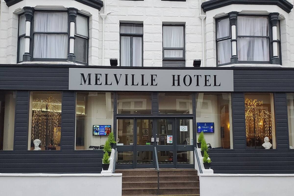 Exterior do Hotel Melville com fachada clássica, janelas grandes e entrada imponente.
