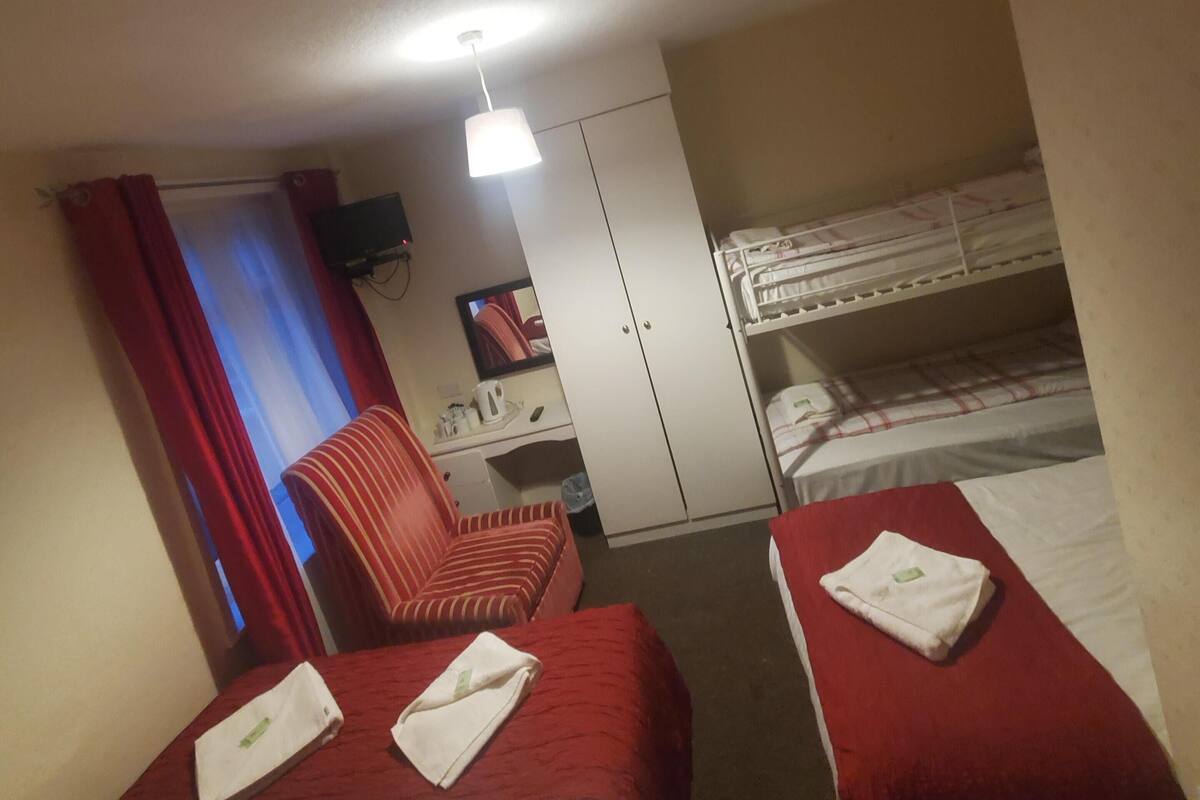 Quarto de hotel com duas camas, uma escrivaninha, uma cadeira e um guarda-roupa.