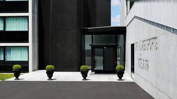 Um edifício moderno com fachada curva, entrada de vidro e uma placa com a inscrição 'The Park Hotel'.