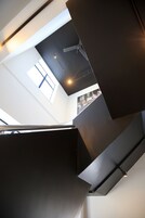Interior moderno com escada que leva a um mezanino, apresentando um claraboia e vista para a cidade.