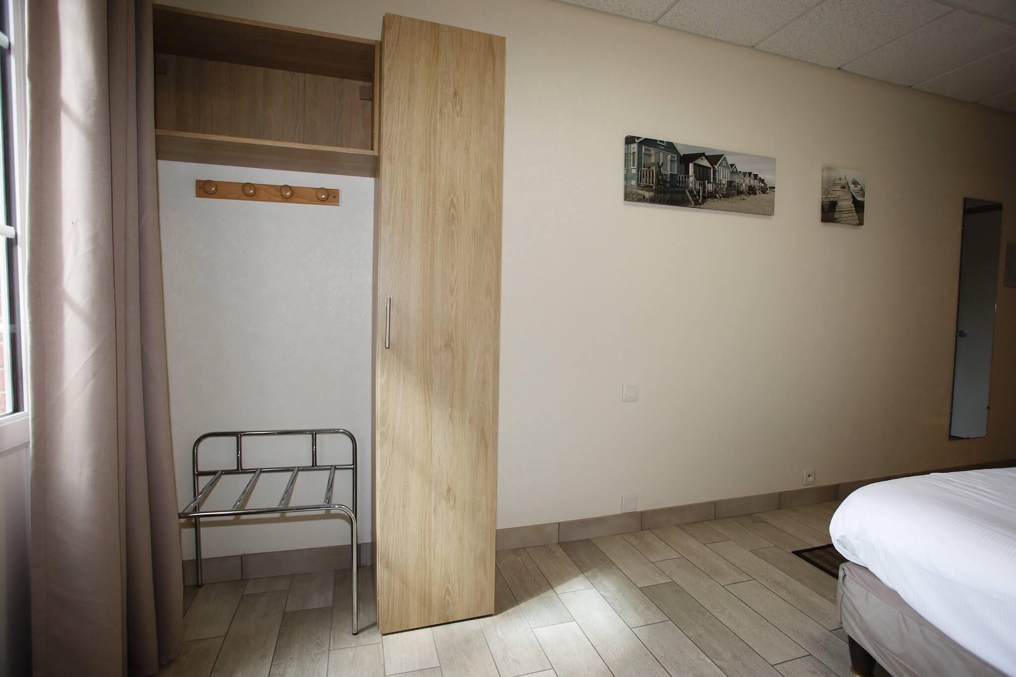 Quarto com cama, guarda-roupa e um banco de metal.