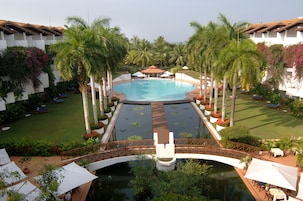 Resort com piscina central, palmeiras e áreas de estar ao ar livre.