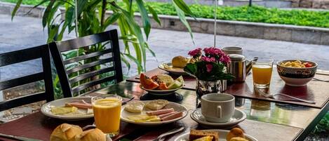 Mesa posta para o café da manhã, com pratos de comida, uma xícara de café e um copo de suco de laranja.