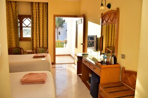 Quarto de hotel com duas camas, uma escrivaninha com espelho, televisão e vista para a varanda.