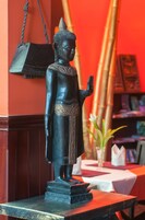 Estátua de uma figura sentada com a mão levantada, possivelmente um símbolo religioso ou cultural, colocada sobre um pedestal.