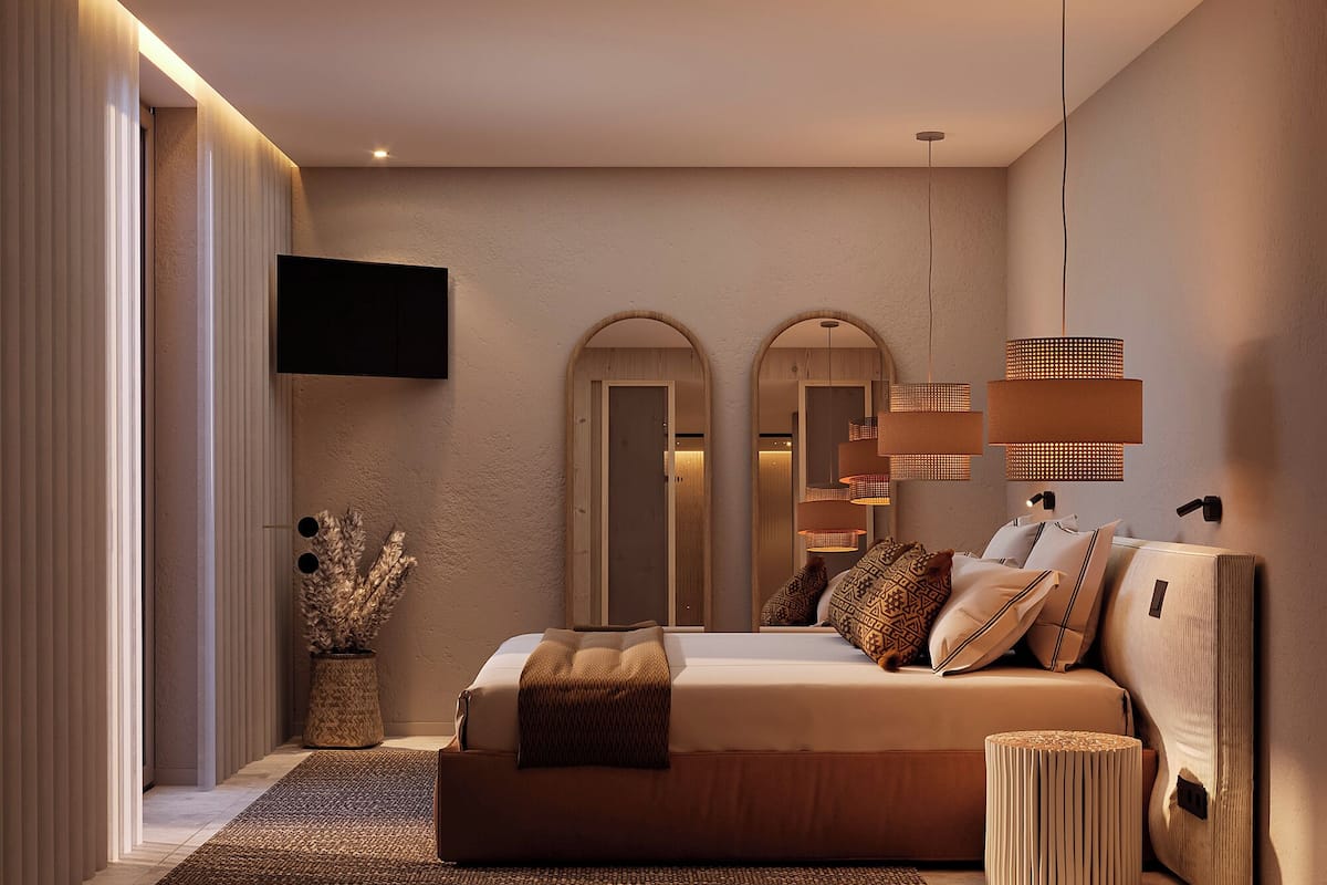 Um quarto moderno com uma cama grande, uma televisão de tela plana na parede e uma luminária singular sobre a cama.