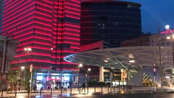 Um hotel moderno com fachada iluminada em vermelho e entrada curva marcante.
