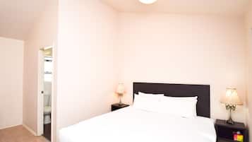 Quarto com cama, duas mesas de cabeceira com abajures, um criado-mudo e um armário.