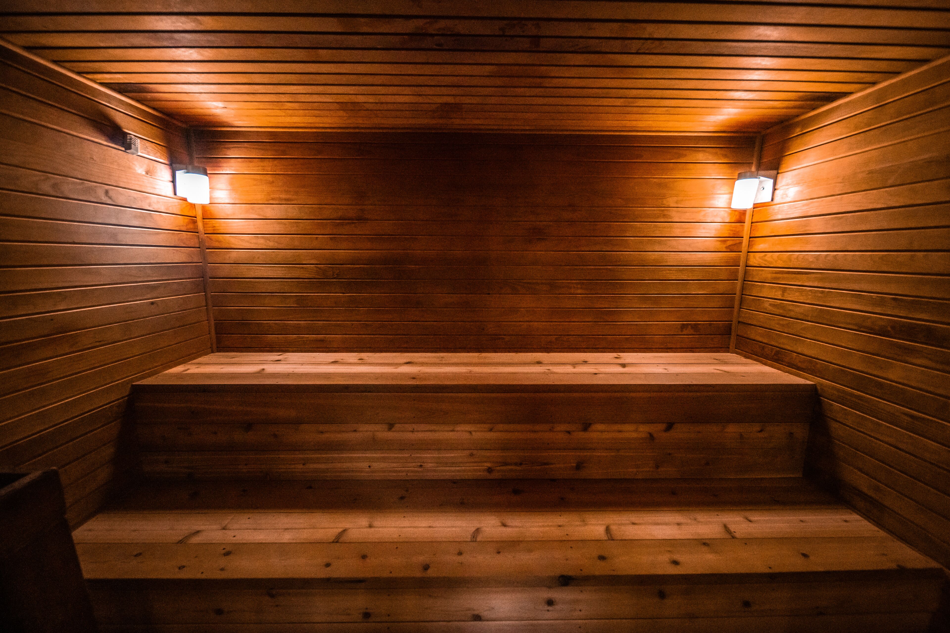 Uma sauna de madeira com degraus que levam a um banco.