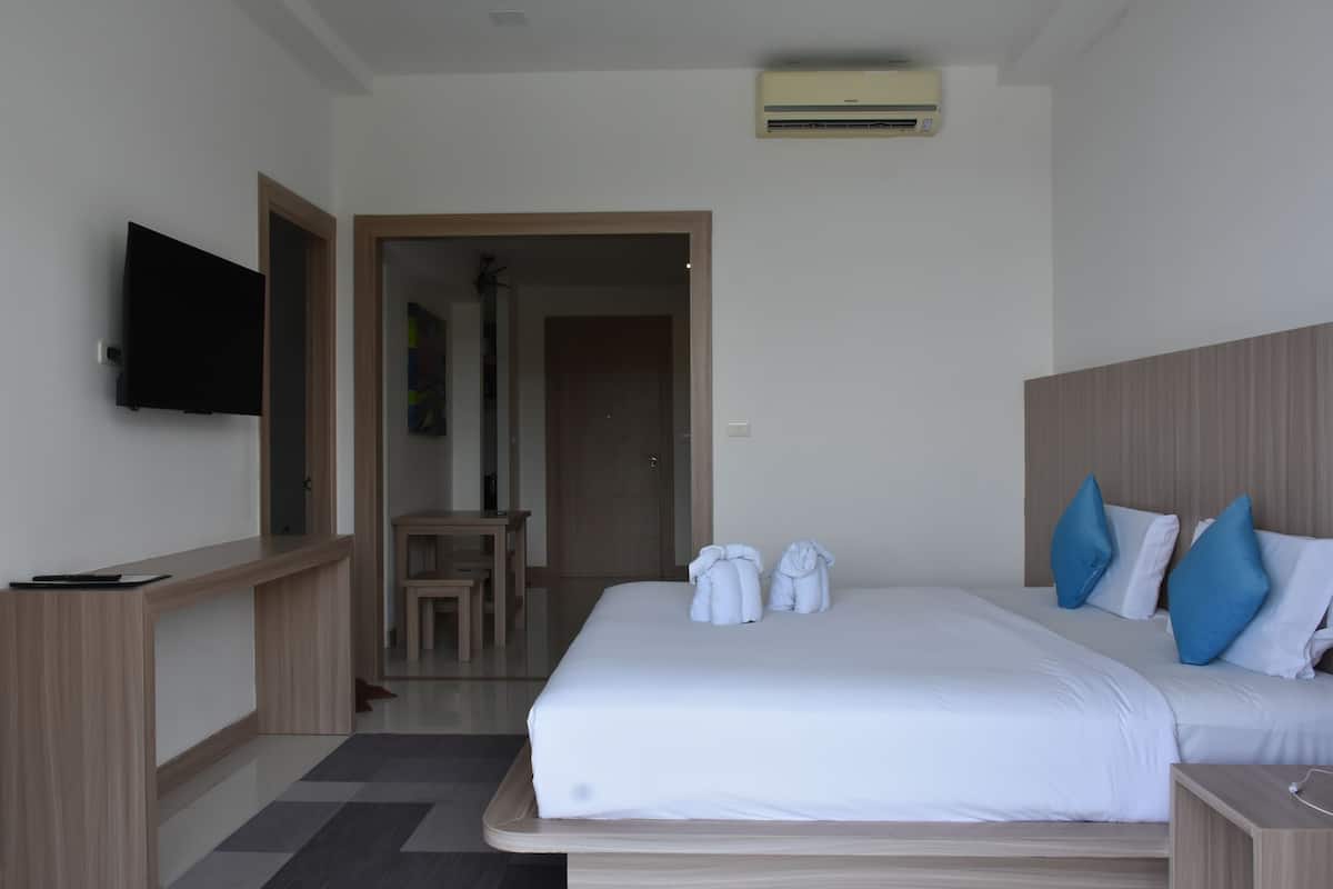 Quarto de hotel com cama, escrivaninha, televisão e ar condicionado.