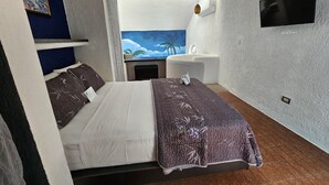 Quarto moderno com cama, pia pequena, televisão e um mural na parede.