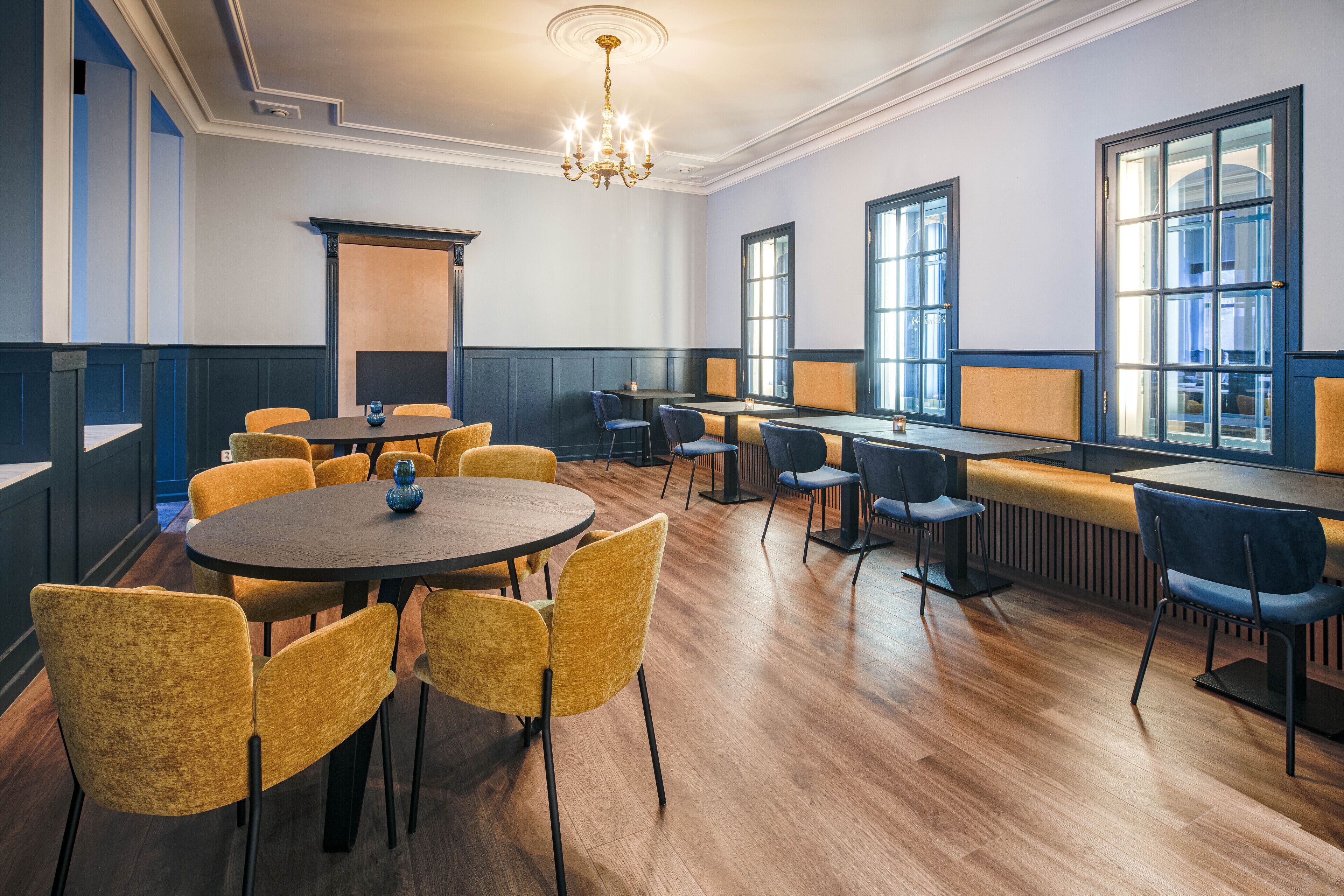 Uma sala de conferências com uma mesa redonda, cadeiras amarelas e um candelabro.