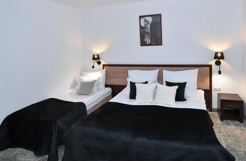 Quarto de hotel com cama, mesas de cabeceira, abajures e um quadro na parede.