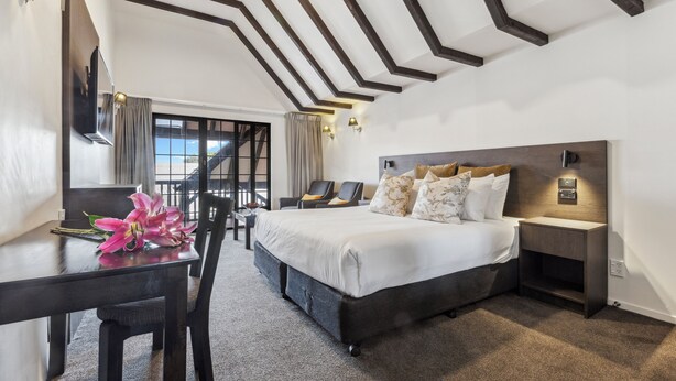 Quarto de hotel moderno com uma cama grande, uma escrivaninha com cadeira e vista para o exterior.