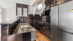 Cozinha moderna com armários escuros, eletrodomésticos de aço inoxidável e uma ilha grande com pia.